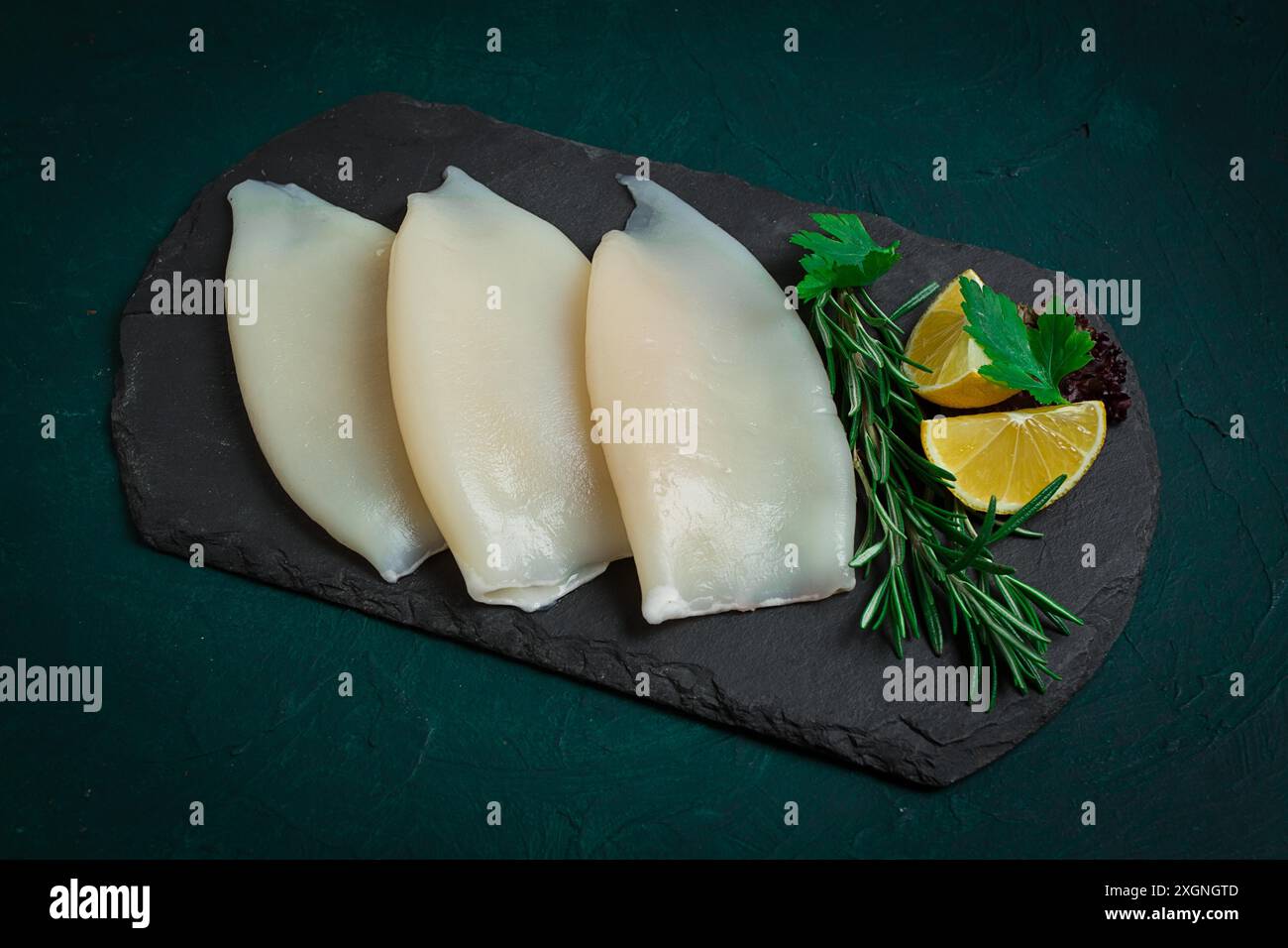 Fresh squid body, raw, three carcasses, top view, on black slate, no ...