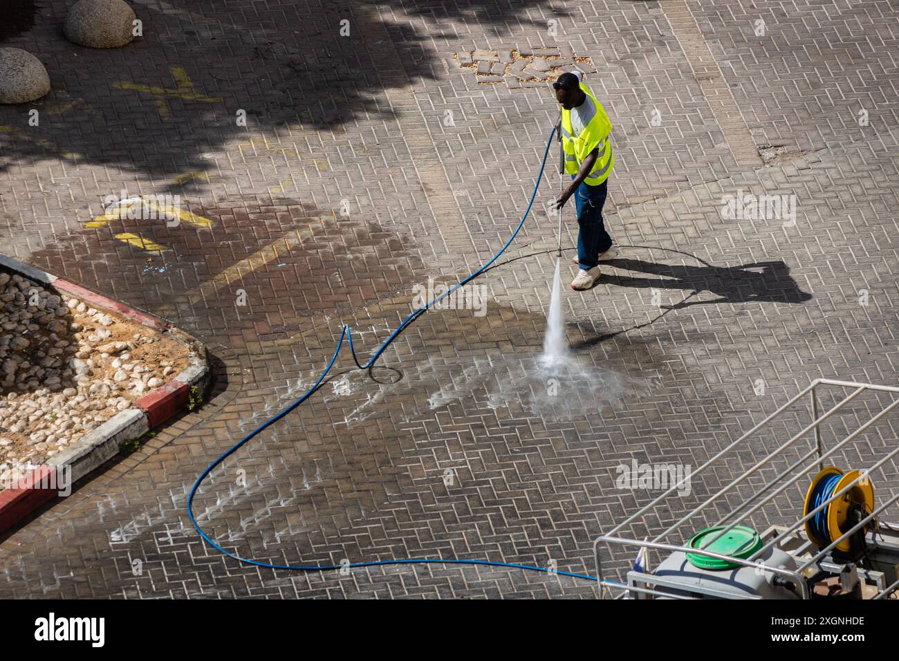 Street cleaner worker in reflective vest washing street with high ...