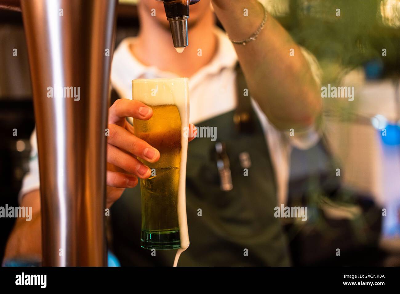 Unrecognizable bartender pouring beer at the restaurant with the foam ...