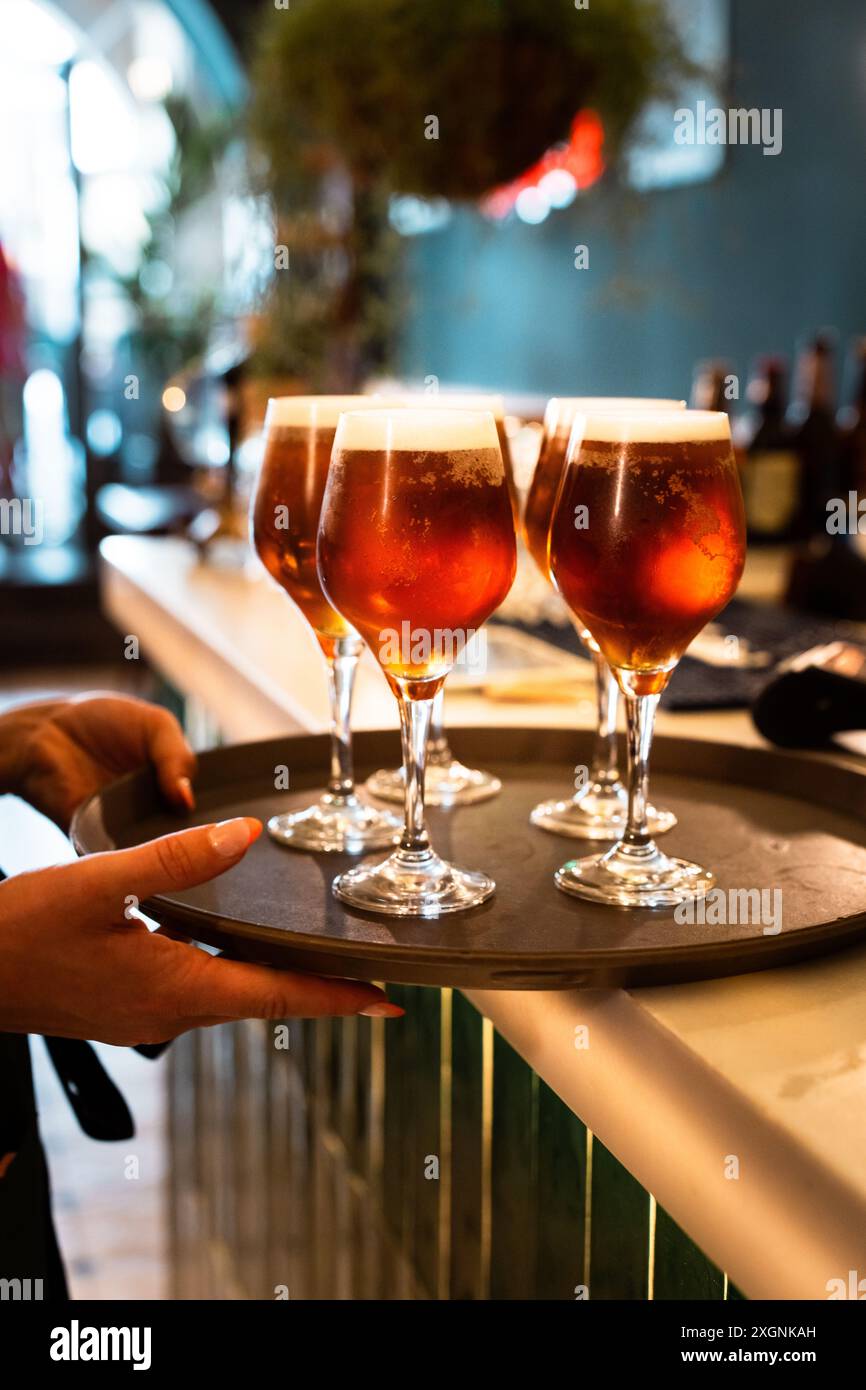 Hands of a woman waitress placing the beers on the tray before serving ...