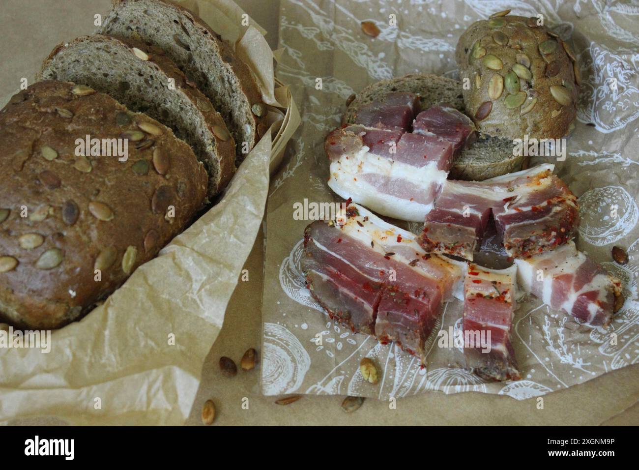 Rustic scene with sliced seed bread and various slices of bacon on ...