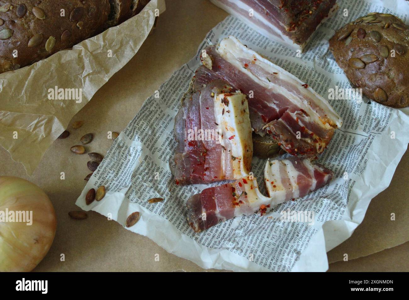 Rustic setup with thick slices of bacon on crumpled paper next to bread ...