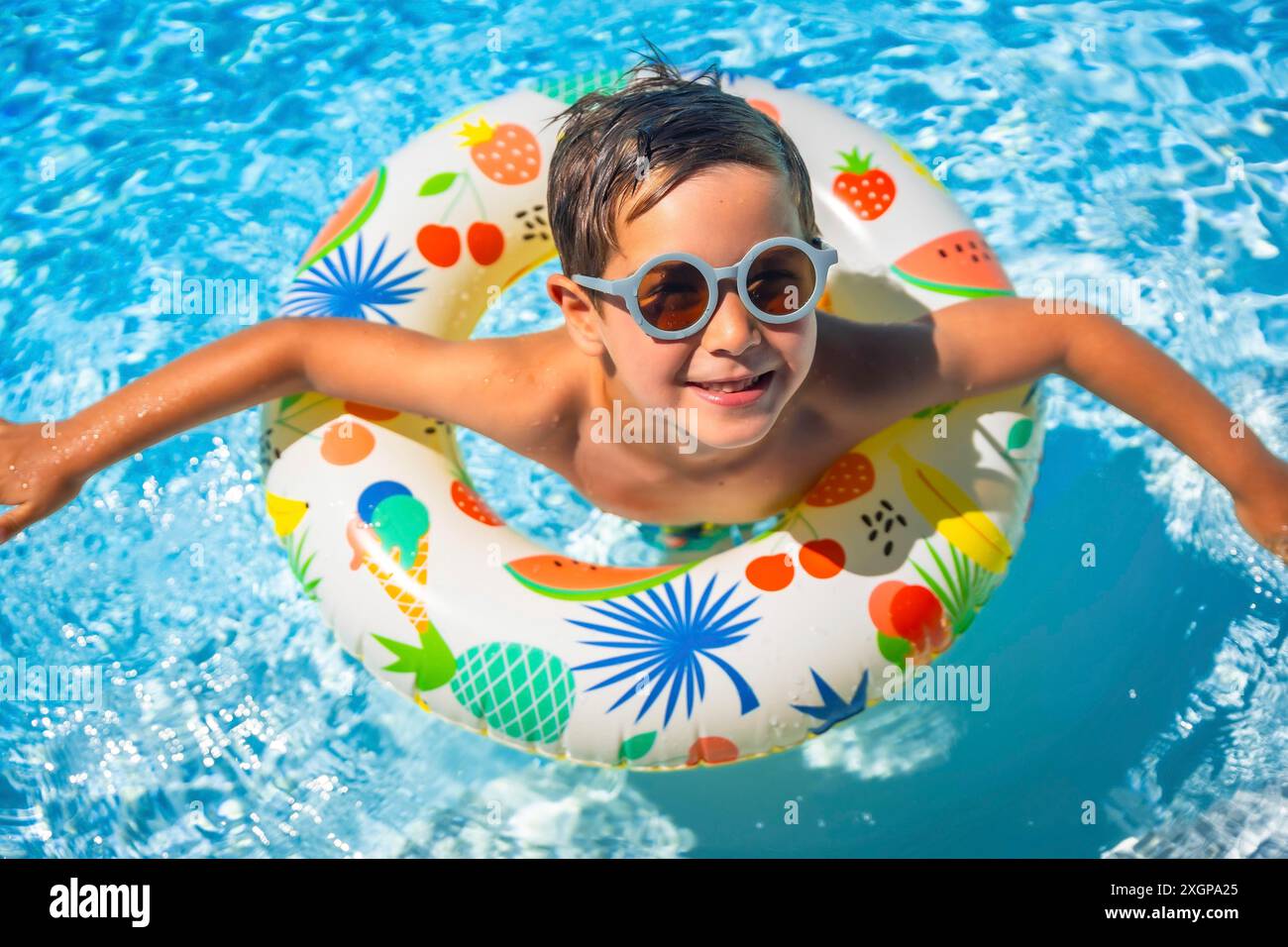Top view of a happy young boy inside a blue swimming pool with swim ...