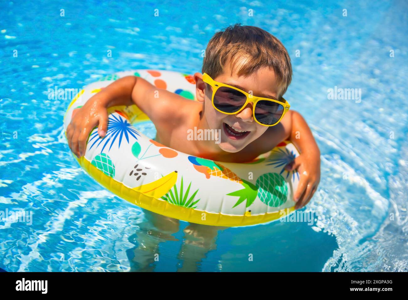 Boy having fun in the swimming pool with a floating rubber ring in ...