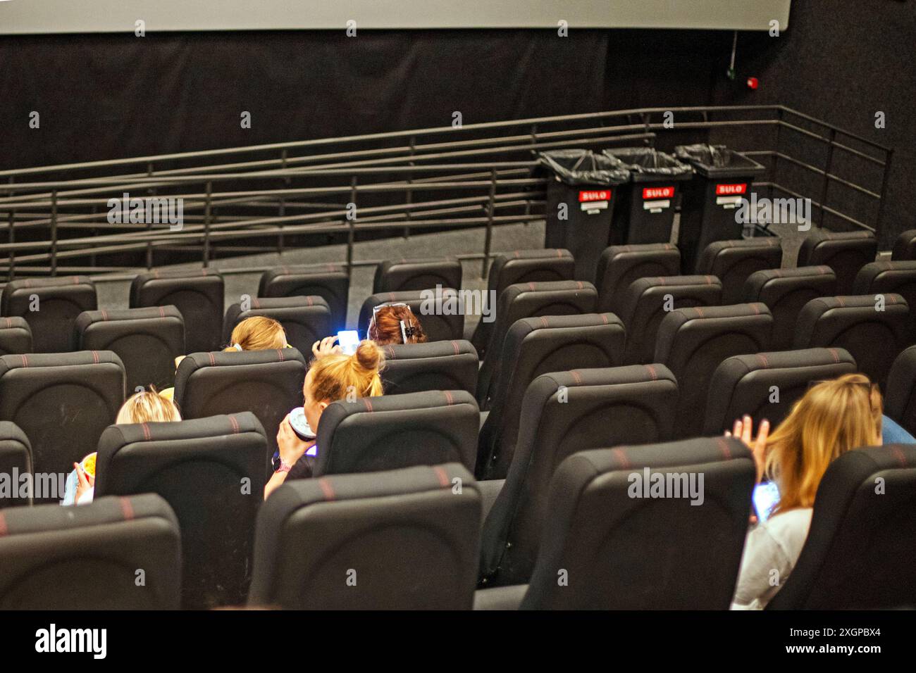 spectators sit in the cinema hall wearing 3D glasses with popcorn and a ...