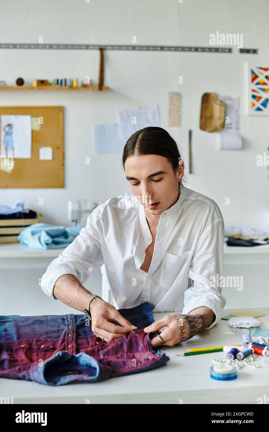 A young man meticulously repairs a vintage denim shirt in his ...