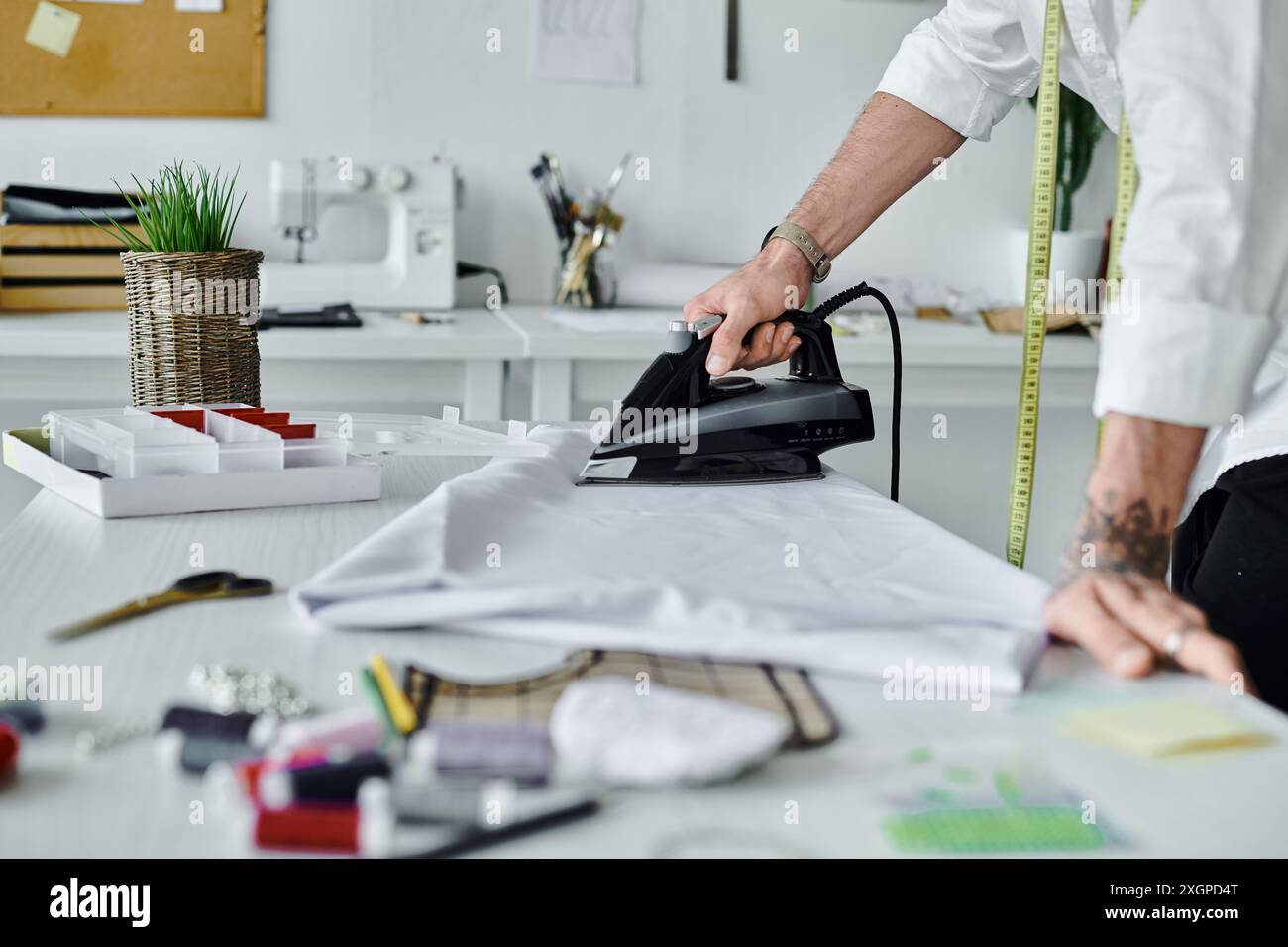 A young man meticulously irons a piece of fabric in his DIY clothing ...