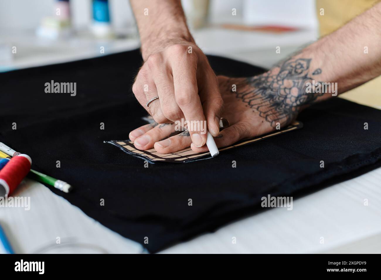 A close-up view of a young mans hands tracing a pattern onto a black ...