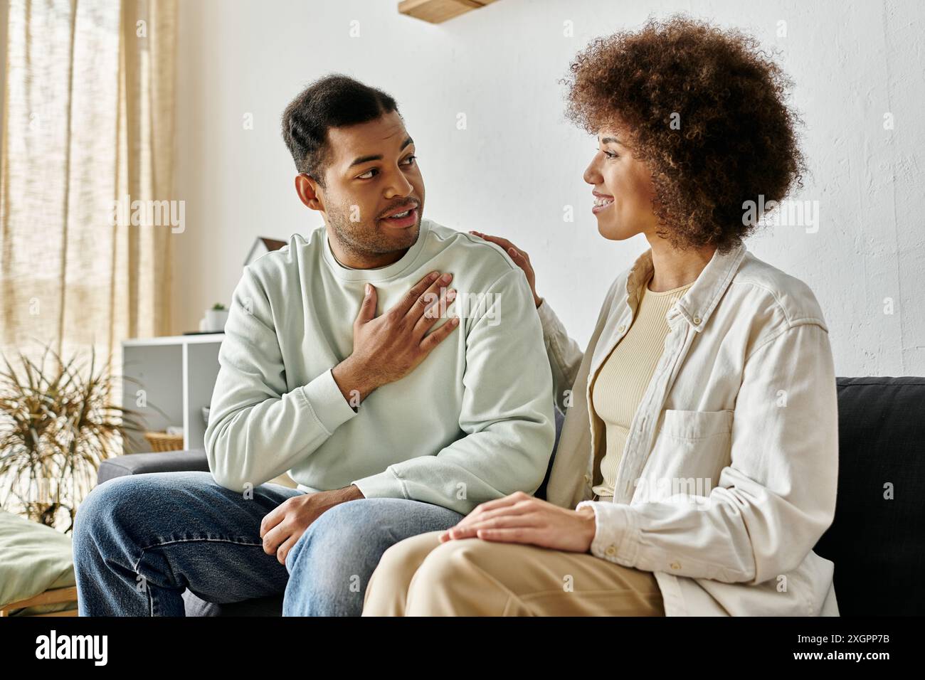 An African American couple sits on a couch, using sign language to ...