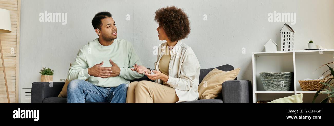 An African American couple sits on a couch, using sign language to ...