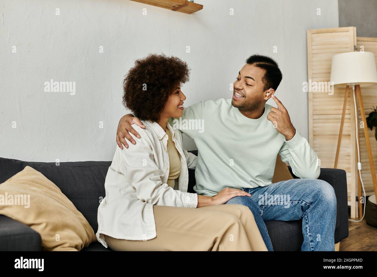 An African American couple sits on a couch, using sign language to ...
