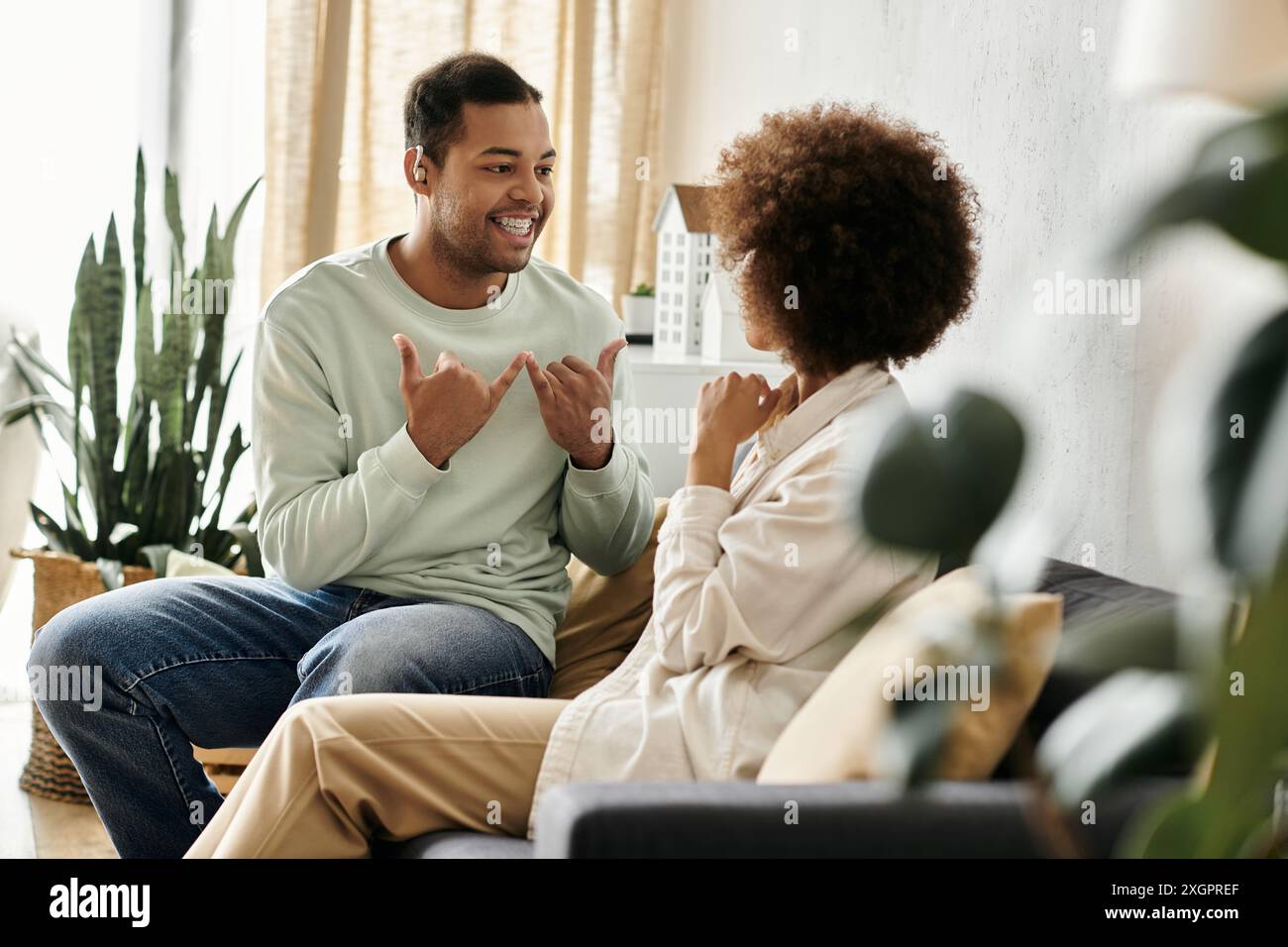 A couple communicates using sign language while sitting on a couch at ...