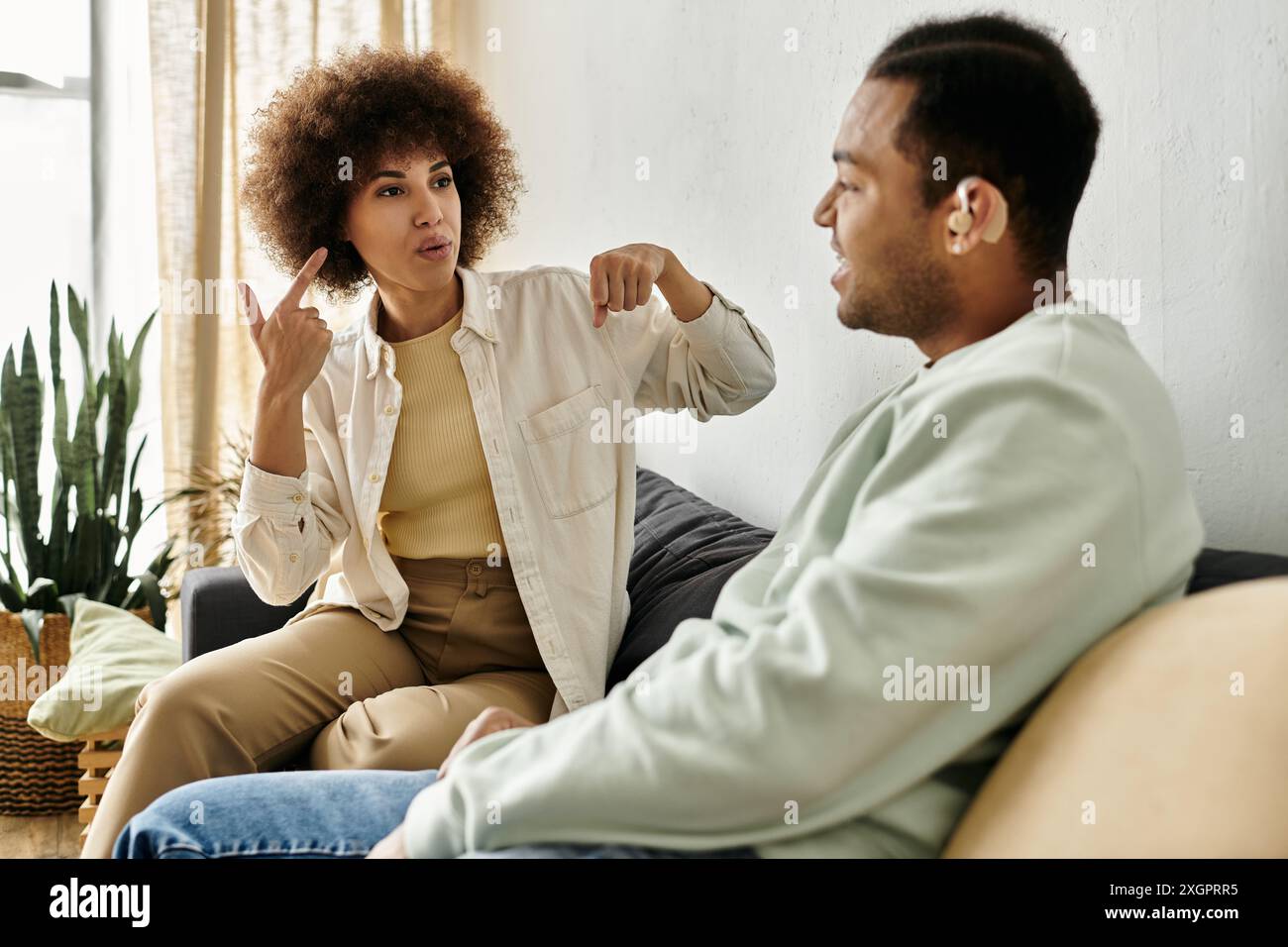 An African American couple sits on a couch, communicating with sign ...