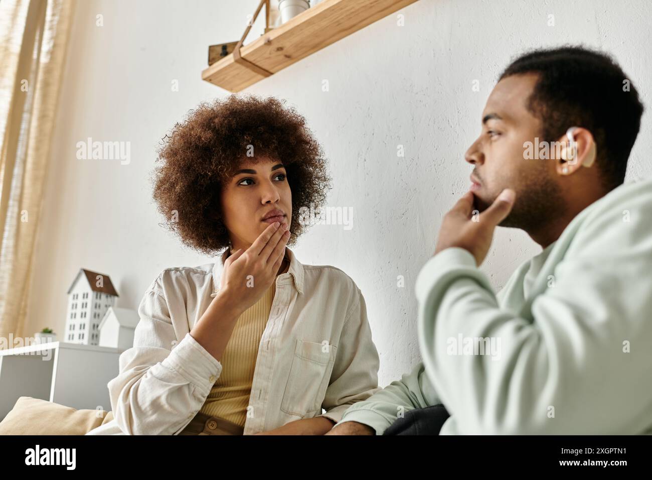 A couple sits at home, using sign language to communicate with each ...