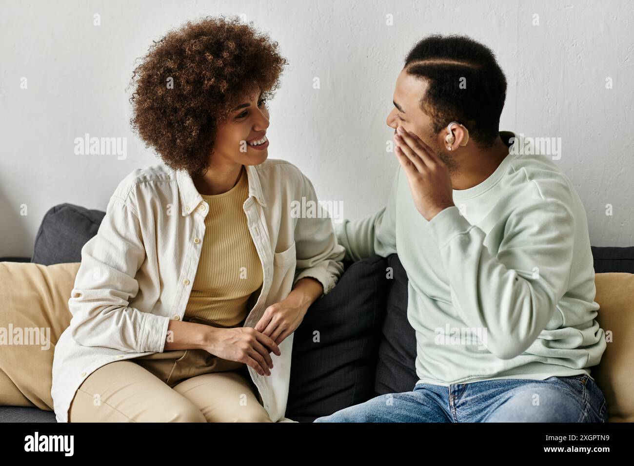 An African American couple sits on a couch and communicates using sign ...