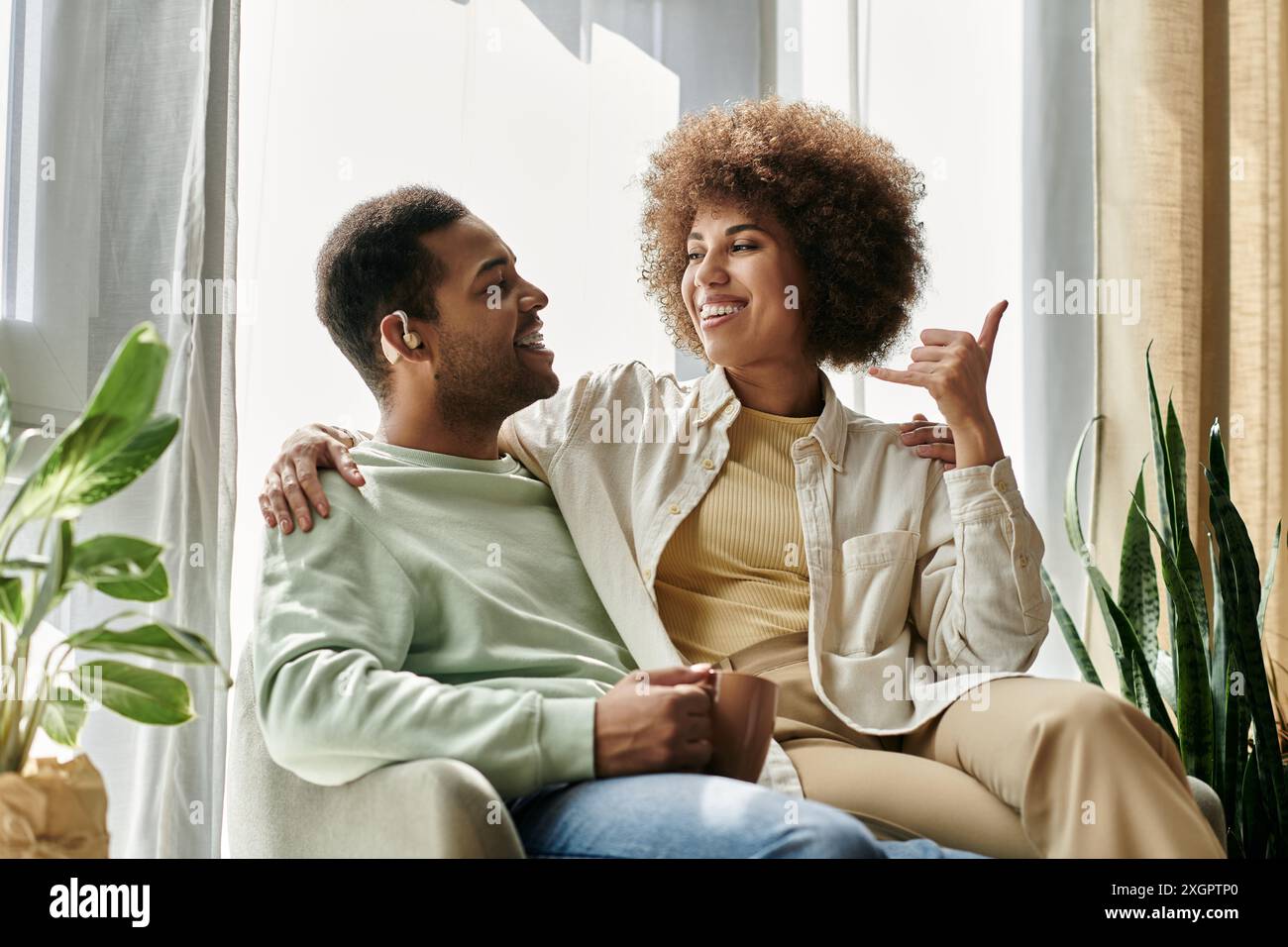 An attractive African American couple sits on a couch, using sign ...