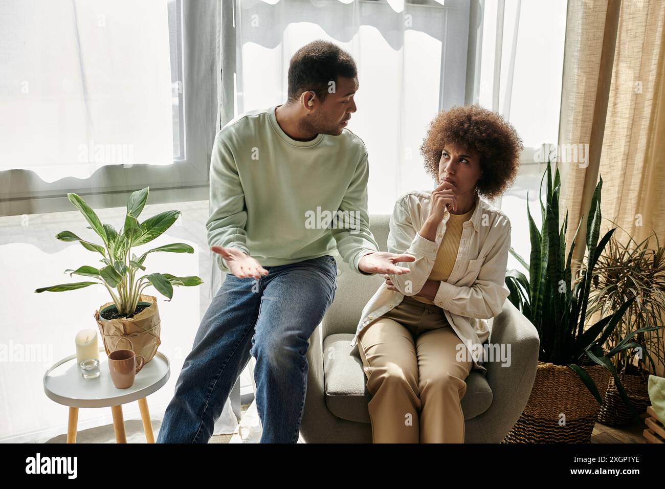 An attractive African American couple sits in their living room, using ...