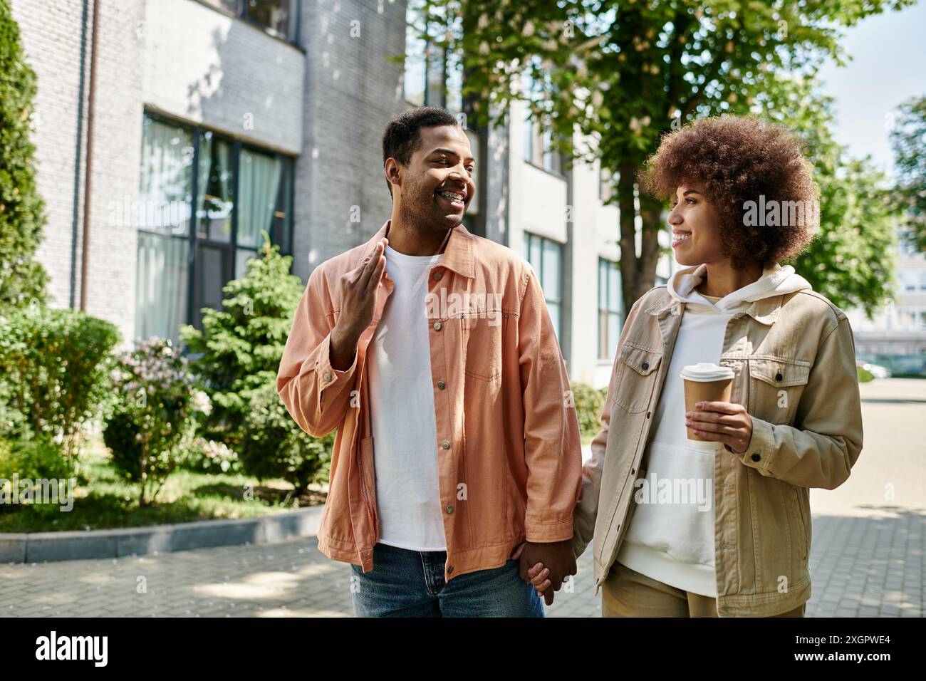 An African American couple walks hand-in-hand, communicating through ...