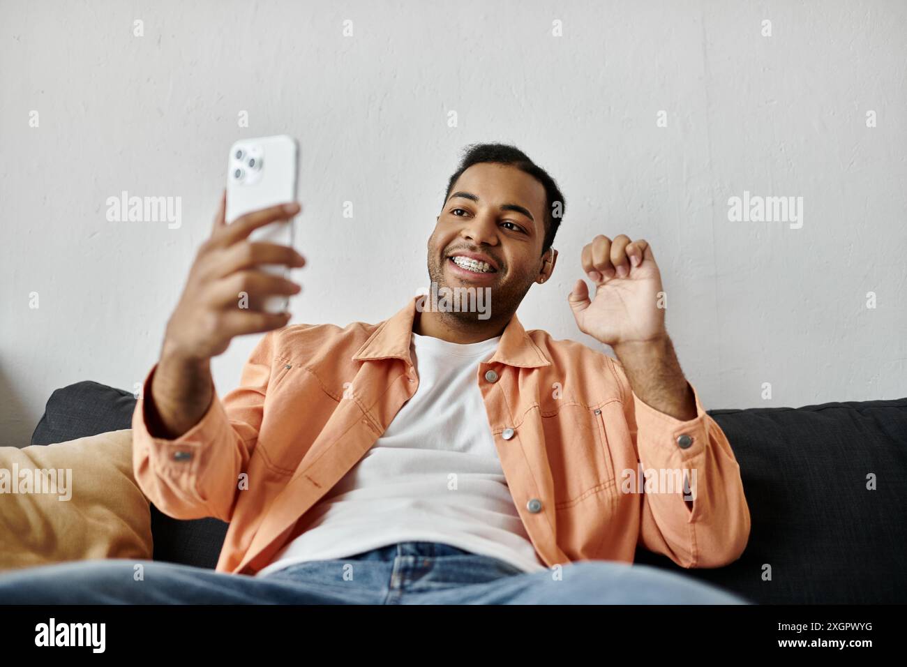 A smiling man uses sign language while video chatting on his phone ...