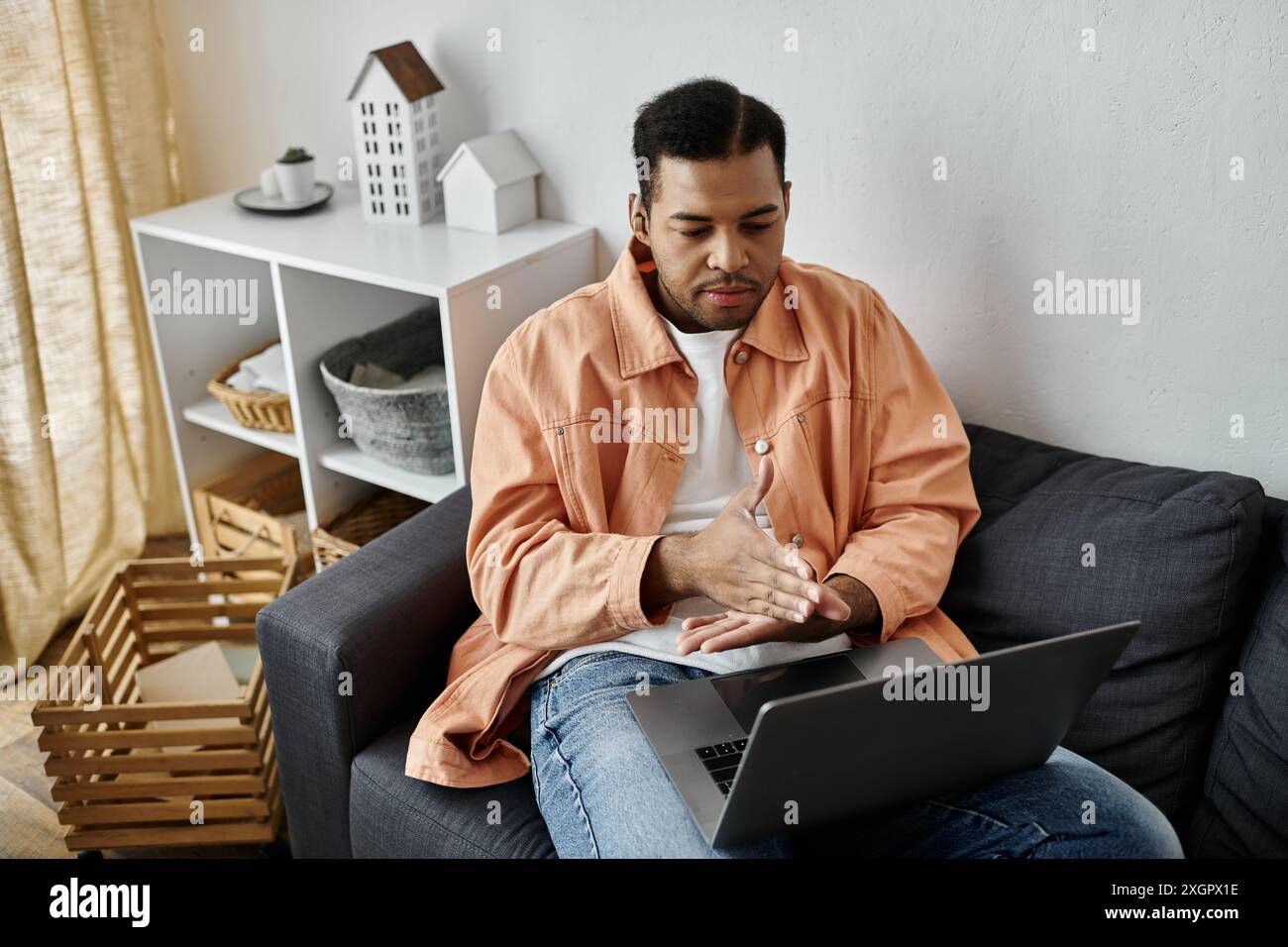 A man sits on a couch, using sign language to communicate Stock Photo ...