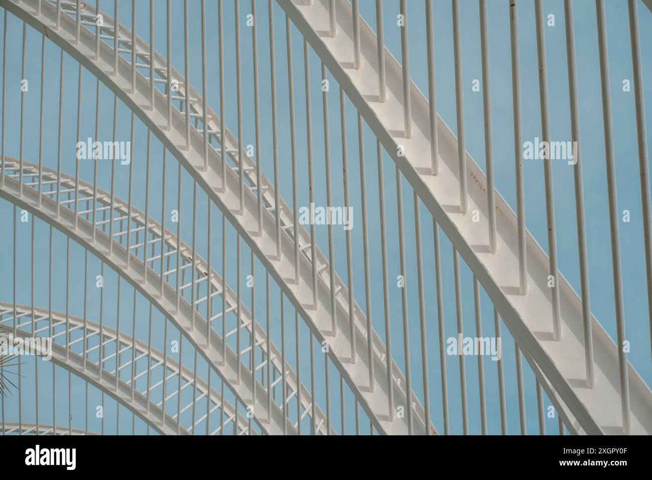 Close-up of a curved metal lattice structure against a clear sky. The ...
