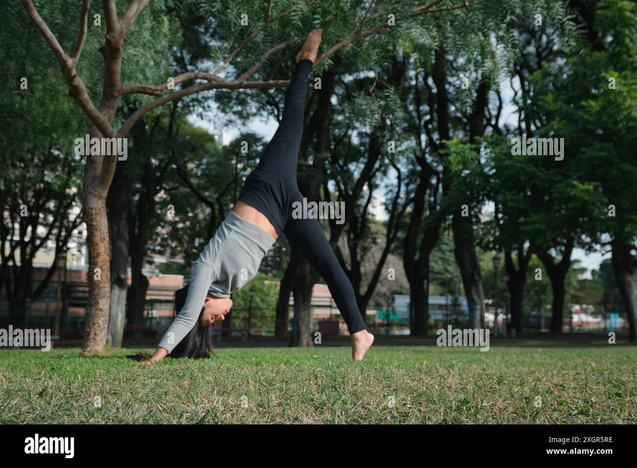 Young Woman Yoga instructor is practicing in park, doing asanas and ...
