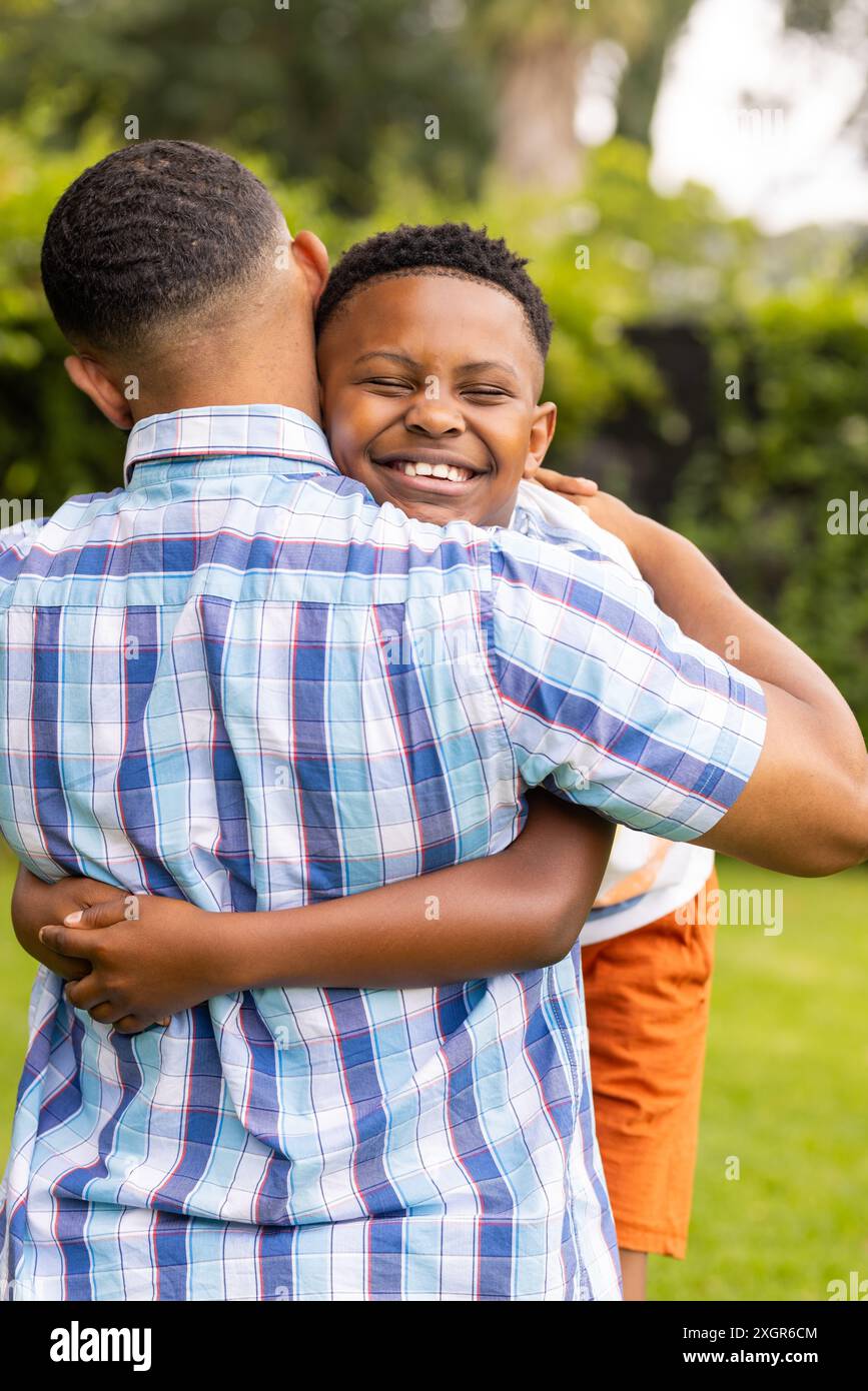 Young African American father embraces an African American son outdoors ...