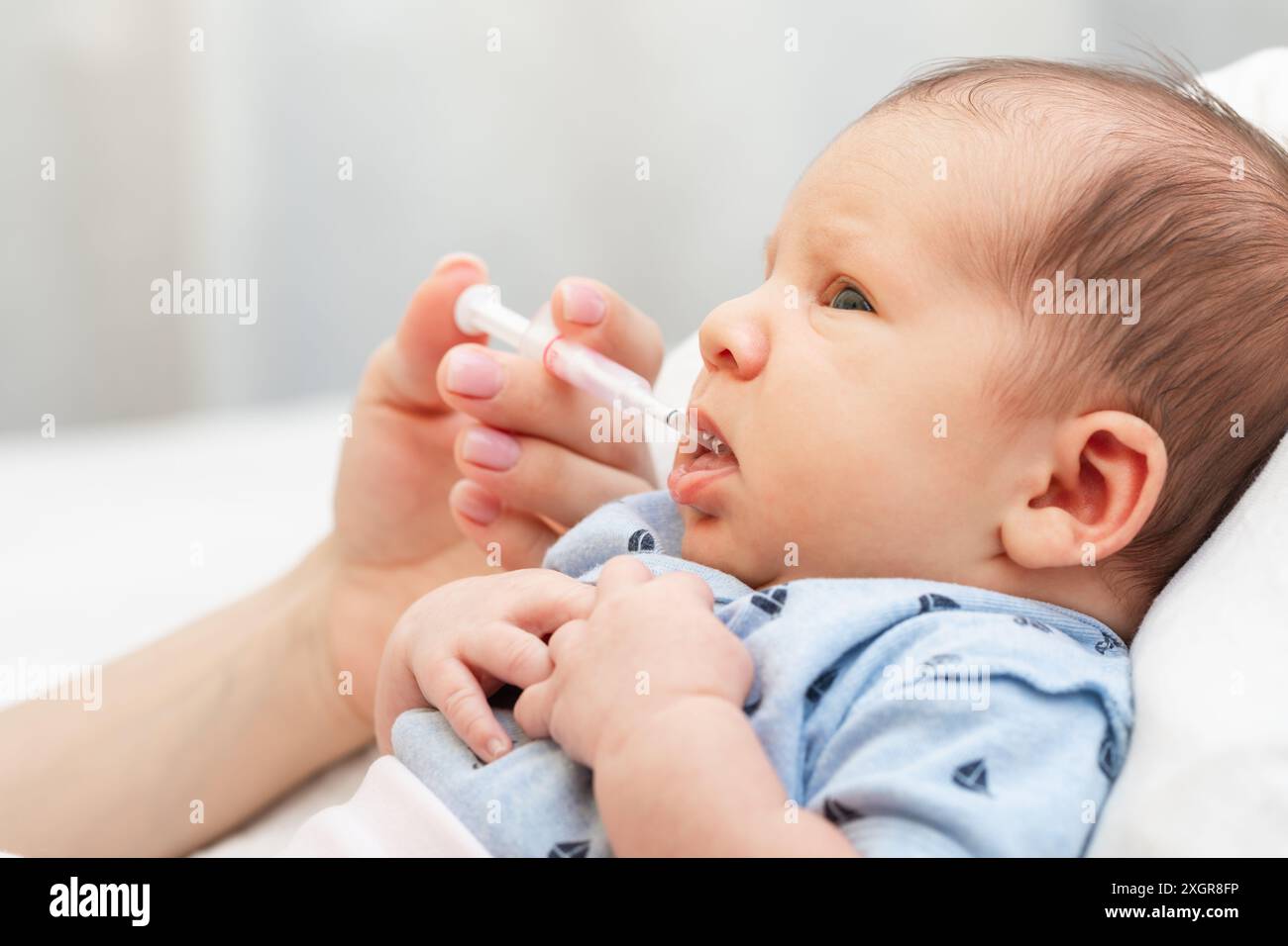 Mother feeding newborn baby with Vitamin K using plastic dropper to ...