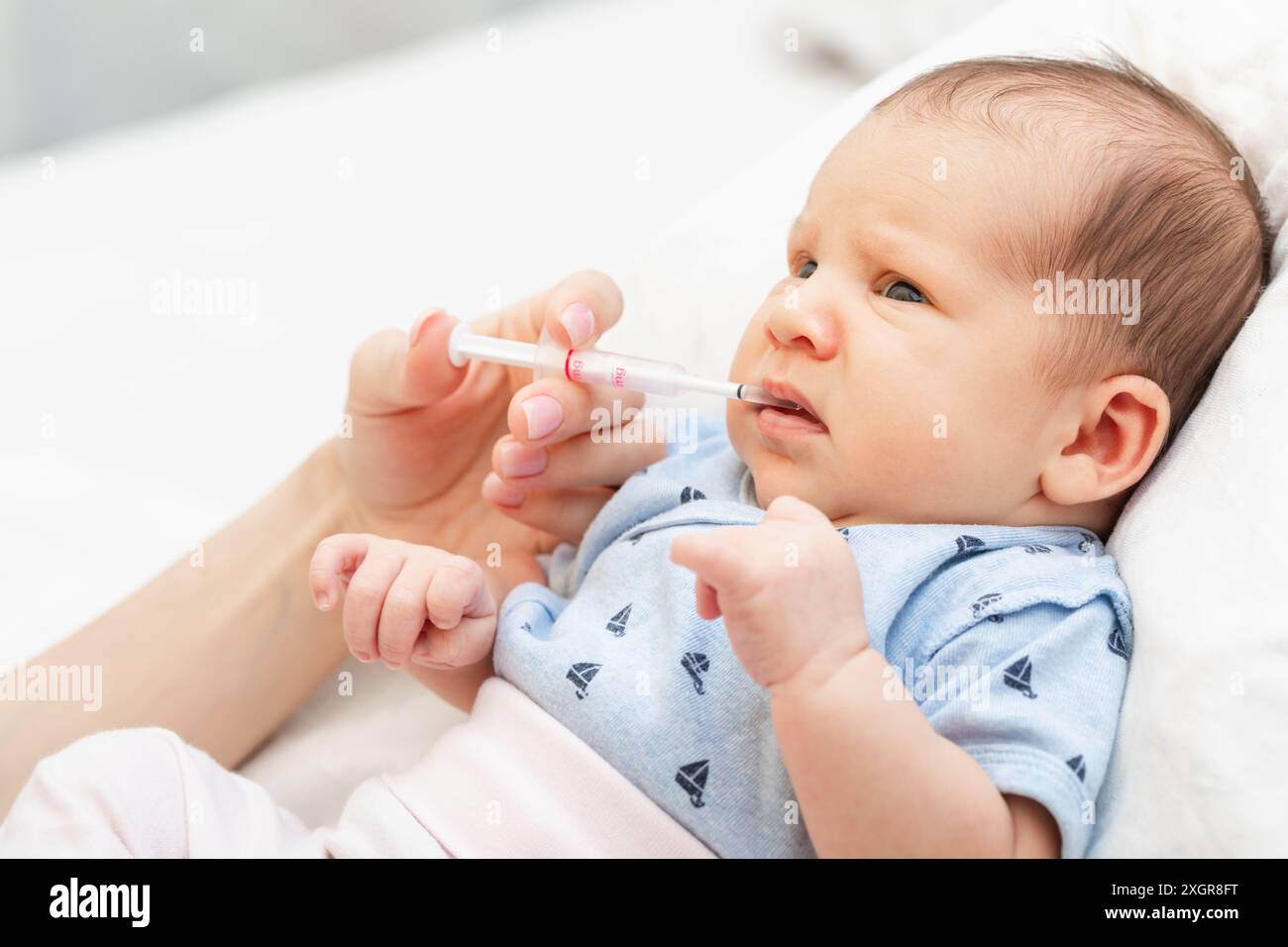 Mother feeding newborn baby with Vitamin K using plastic dropper to ...