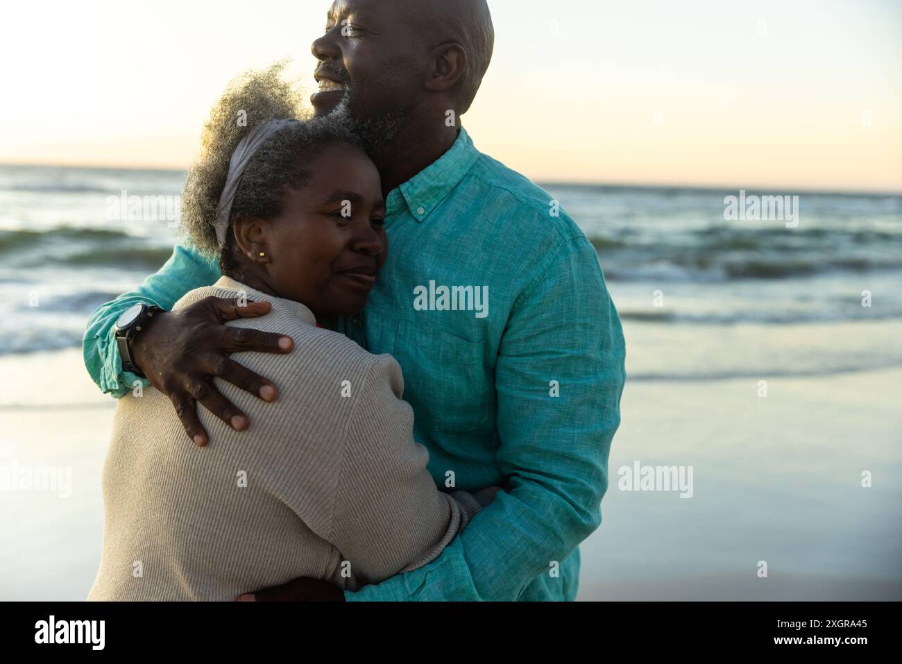 Senior African American couple embraces outdoors at sunset, with copy ...