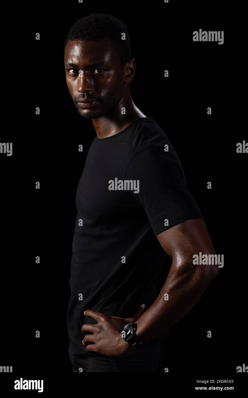 African American man poses confidently on a black background, with copy ...