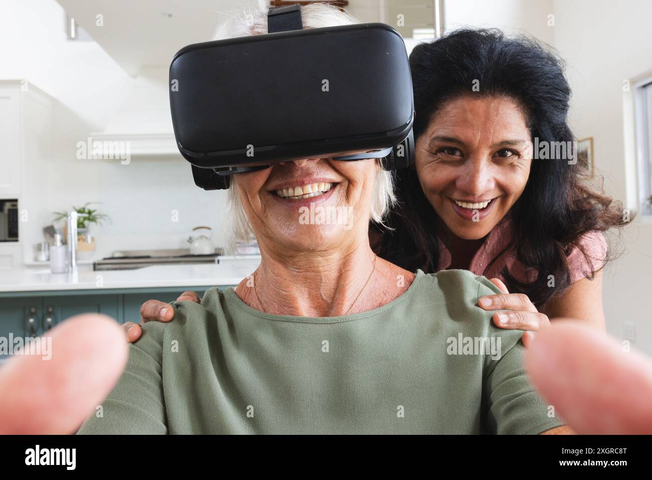 Two happy diverse senior female friends embracing and using vr headset ...