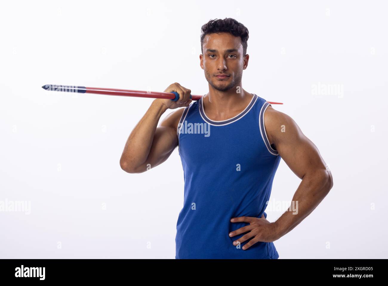 Confident young biracial man poses with a javelin on a white background ...