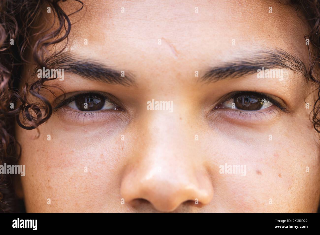 Close-up of a young biracial man's eyes and face, unaltered. His gaze is captivating ...