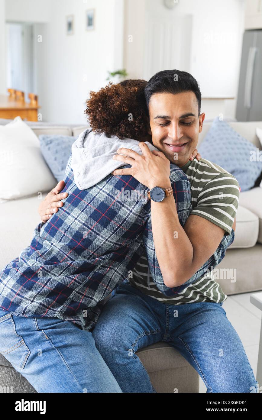 Middle Eastern man embraces his partner, another young man, at home ...
