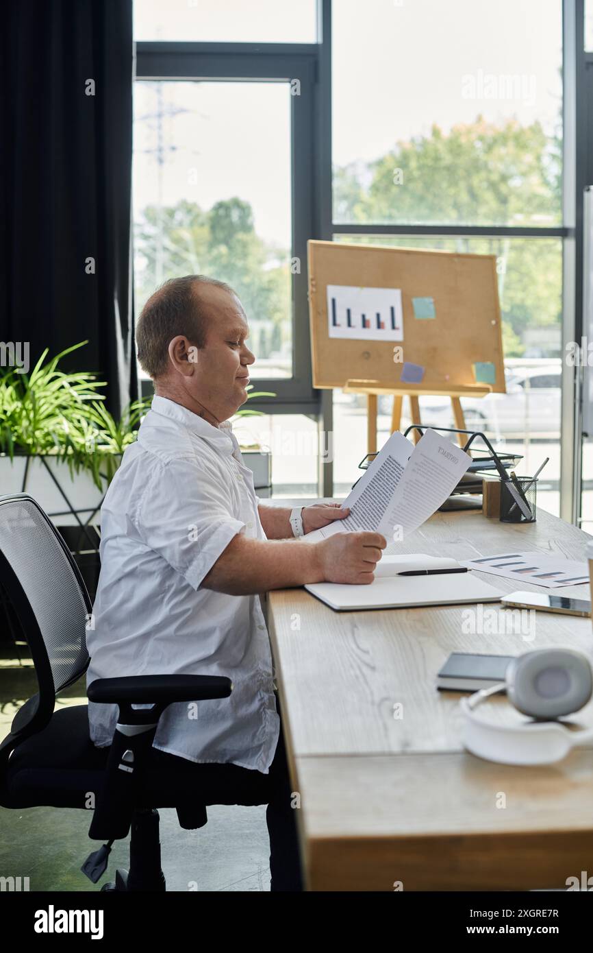 A man with inclusivity sits at a desk in a modern office, reviewing ...