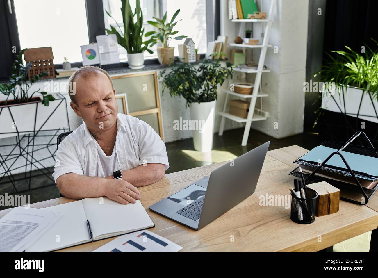 A man with inclusivity works at his desk in a modern office, focused on ...