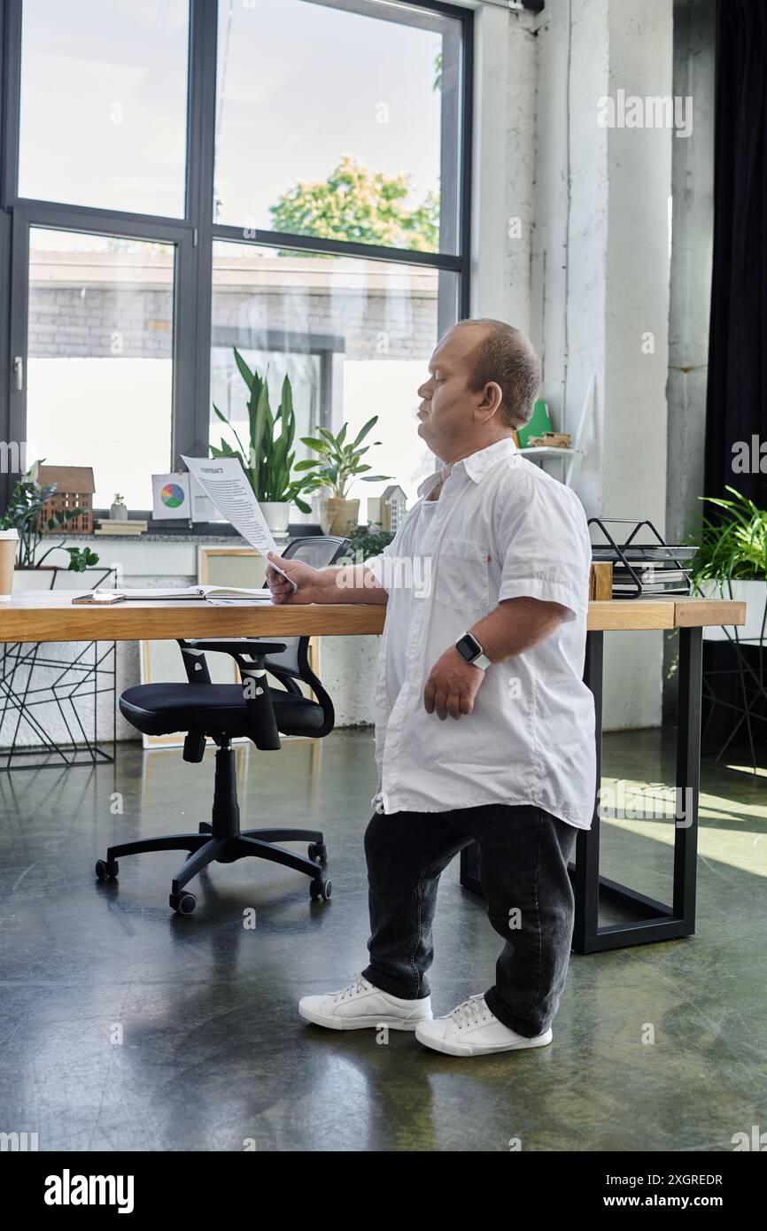 A man with inclusivity stands by a desk in a modern office, reviewing ...