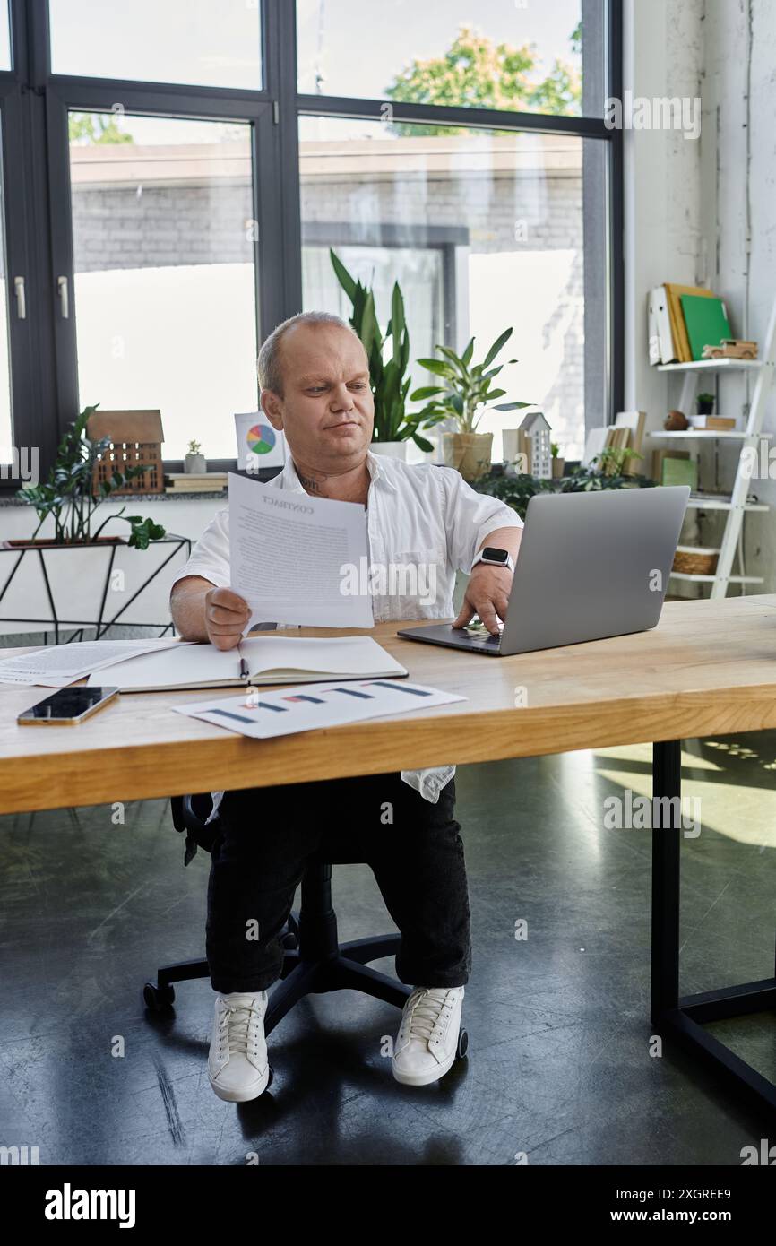 A man with inclusivity sits at a desk in a modern office, working on a ...