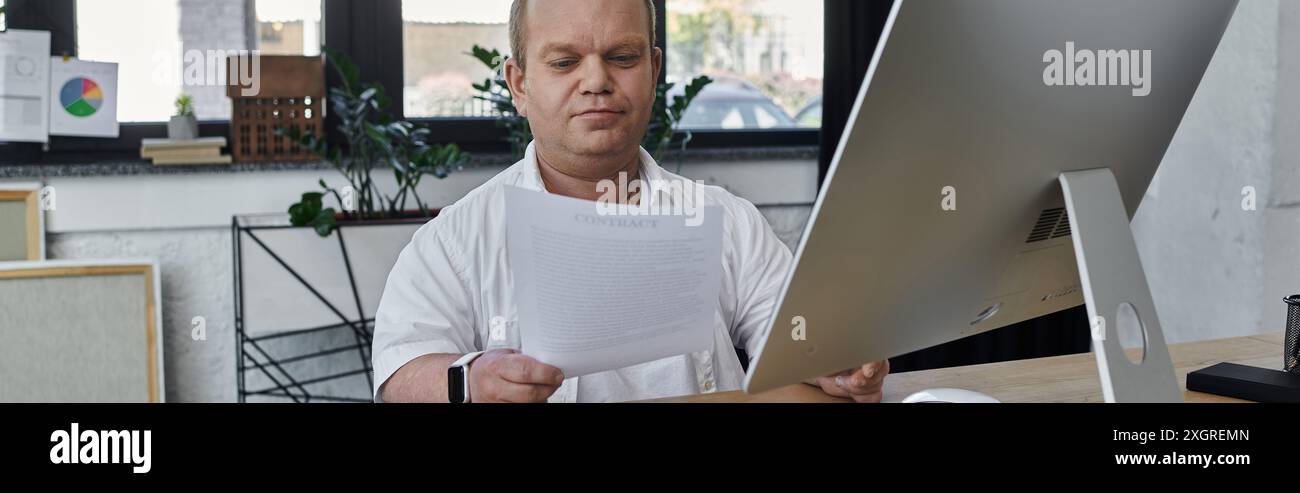 A man with inclusivity sits at his desk, reviewing documents in an ...