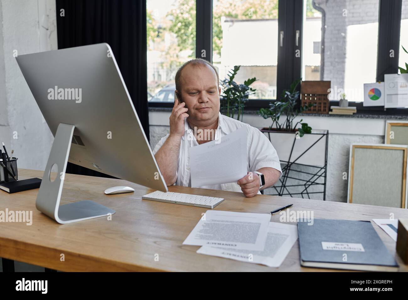 A man with inclusivity sits at his desk in an office, reviewing ...