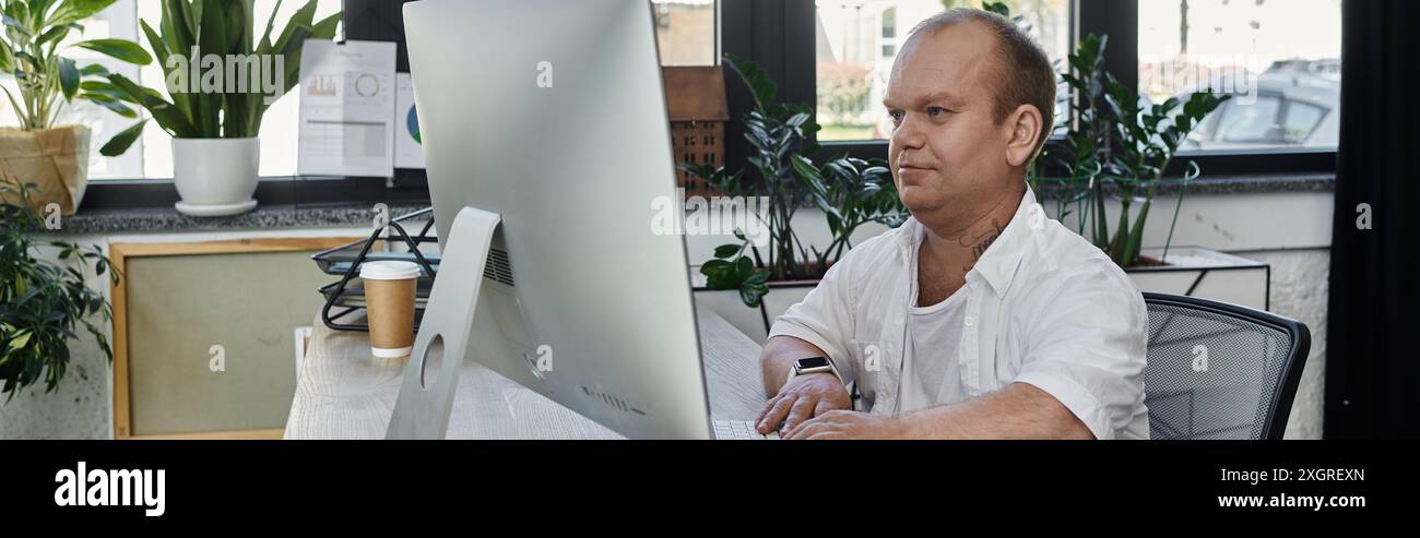 A man with inclusivity is working on a computer in a well-lit office ...