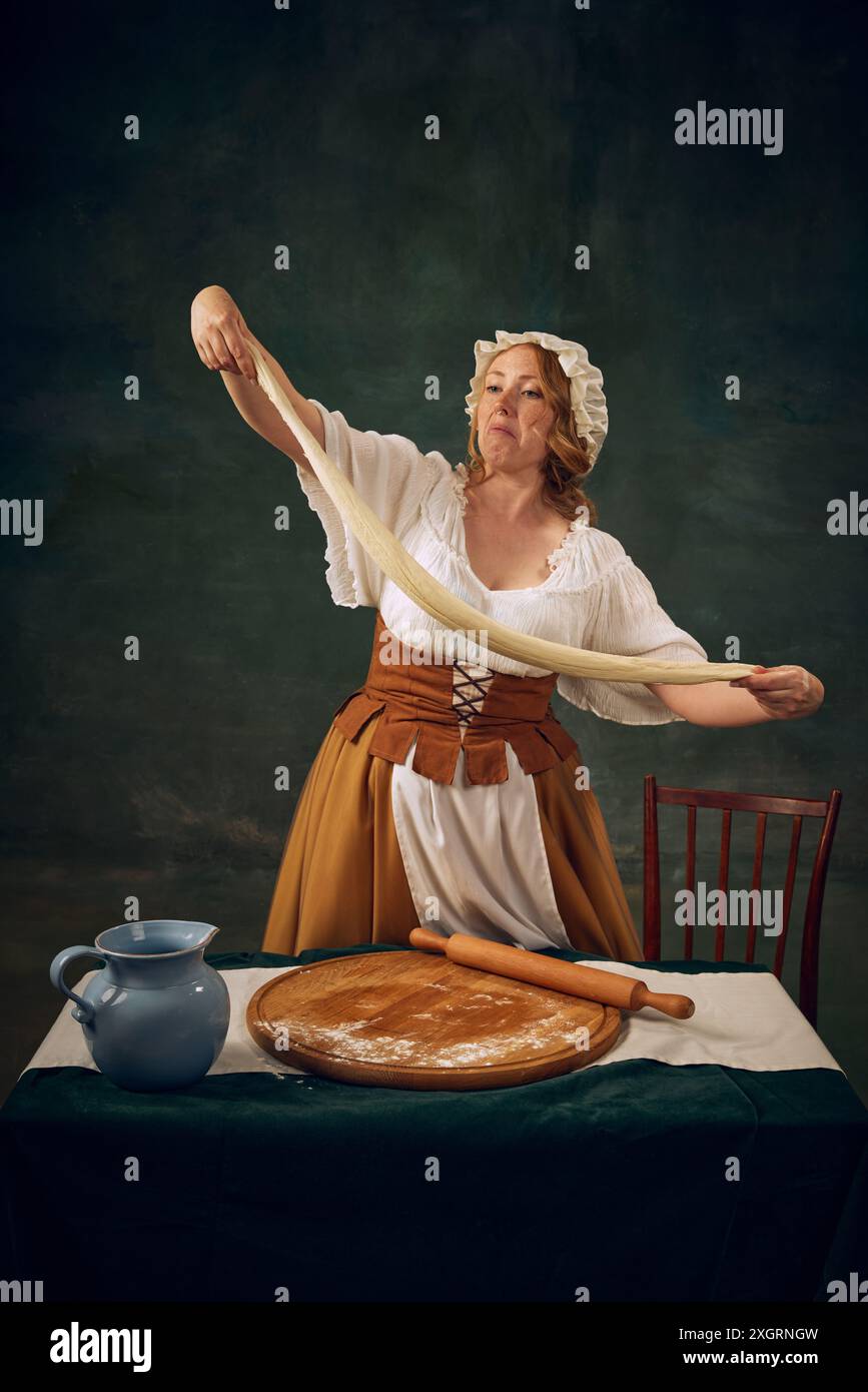 Woman in historical attire making dough for bread, set against dark ...