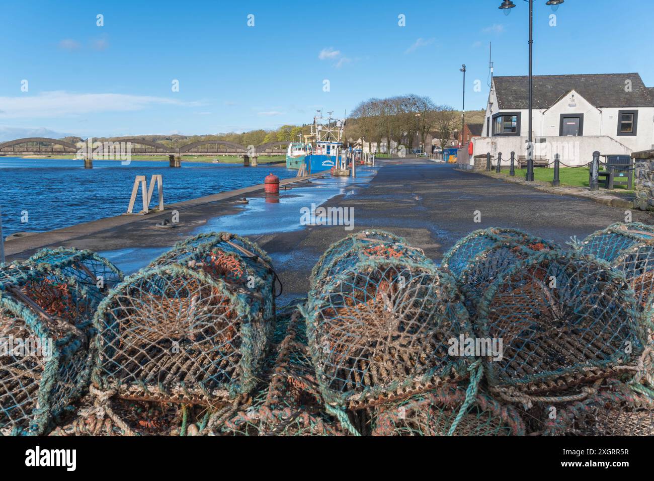 Kirkcudbright harbour with Lobster pots, fishing boats and the road ...