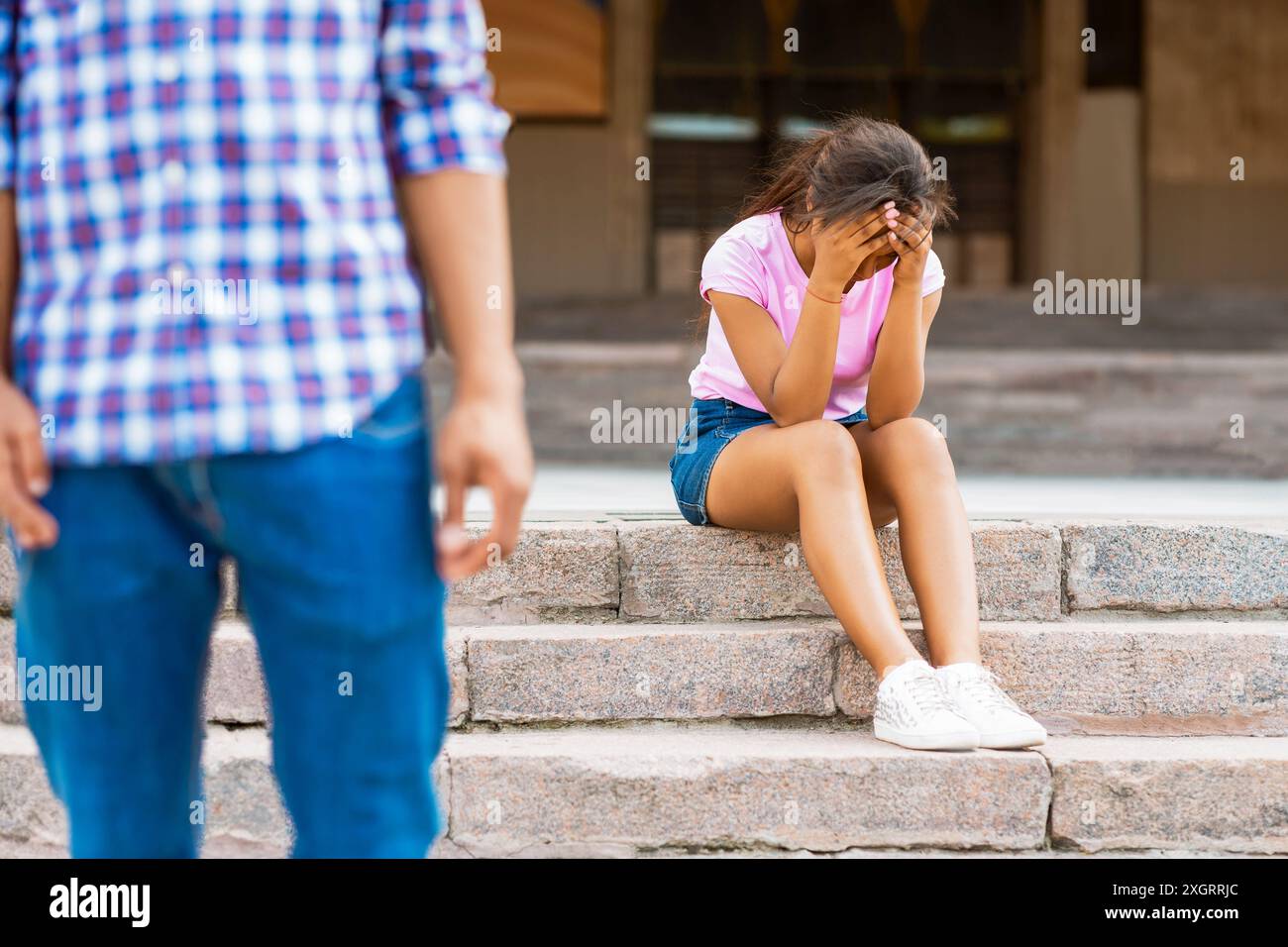 Guy Walks Away From Upset Girl Sitting On Steps Stock Photo - Alamy