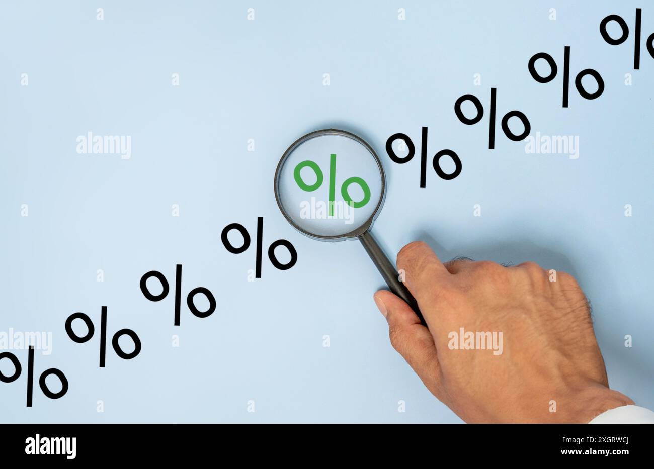 Close-up of a hand holding a magnifying glass over a percentage sign on ...