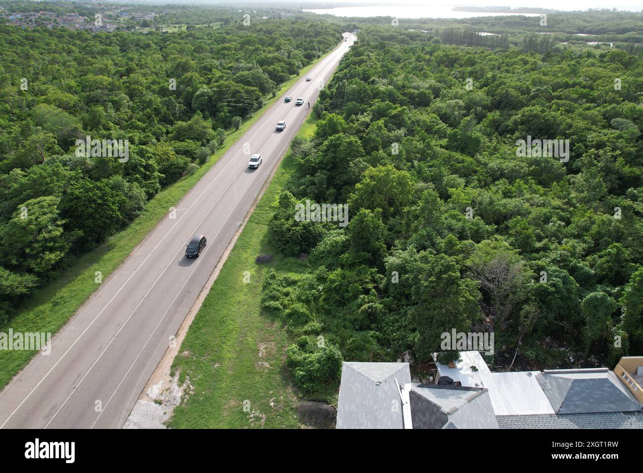 An aerial view of a highway cutting through a dense forest with a few ...