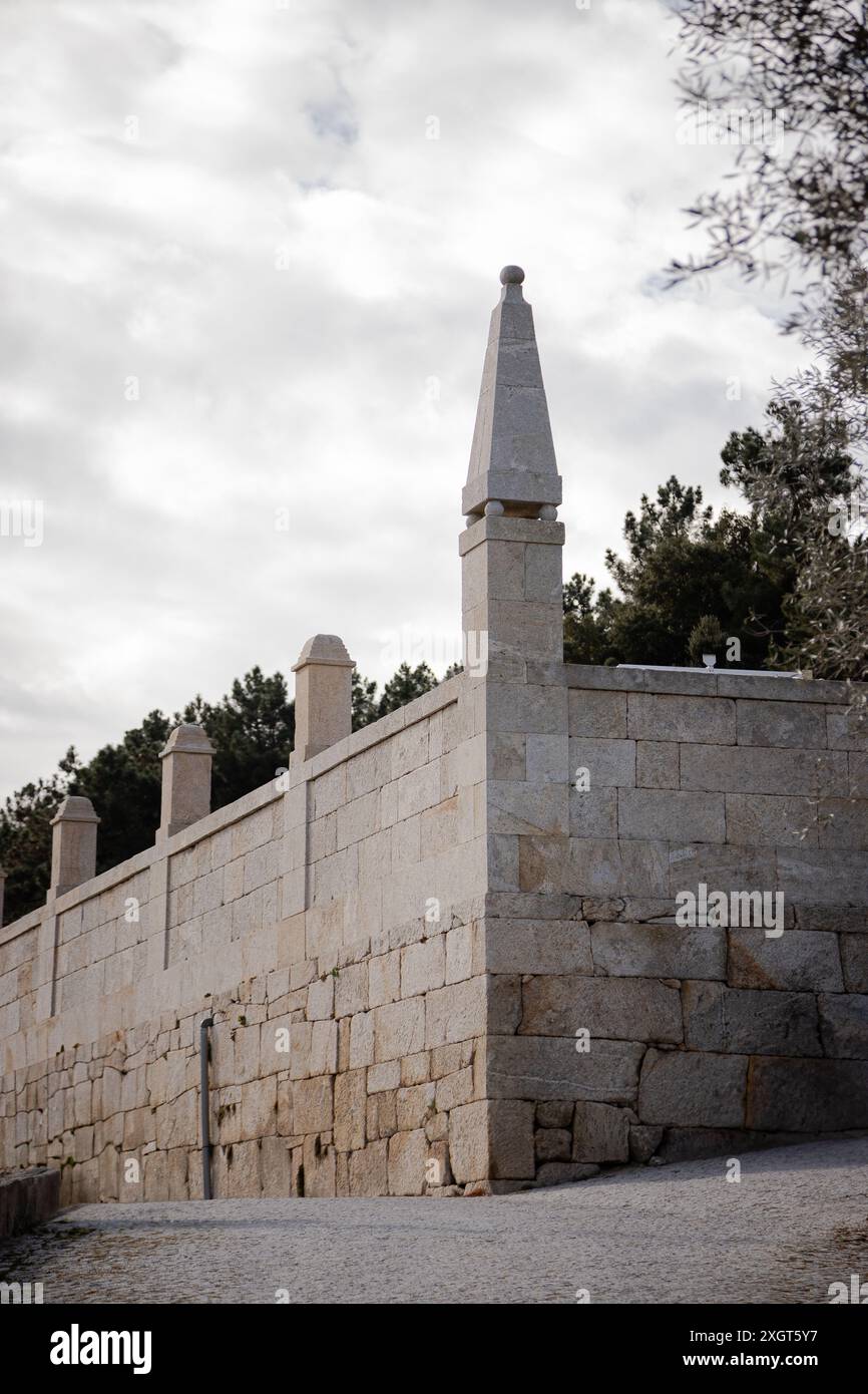 Detail of stone walls and pillars of a historic cemetery under a partly ...