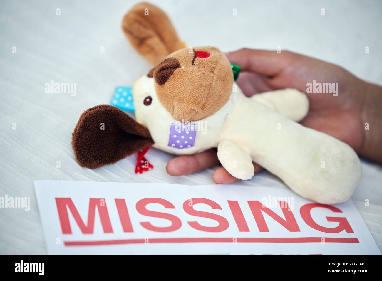 Teddy bear, sign and missing person with hand on bed in house for ...