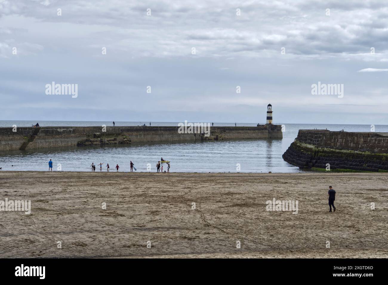 people on the sandy beach within the harbour wall at Seaham, County ...
